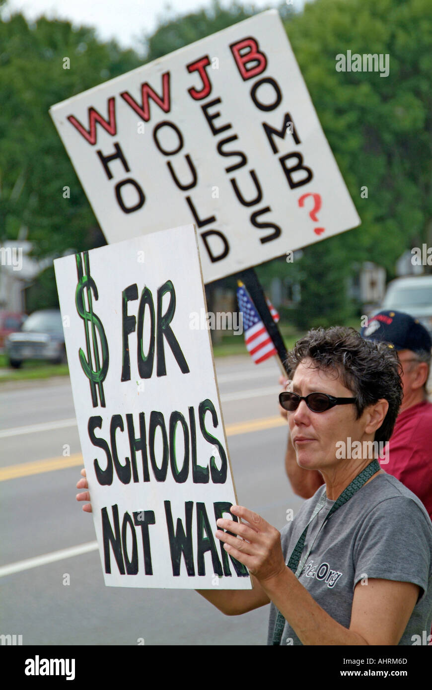 Protesters line a busy city street holding signs to protest war and ...
