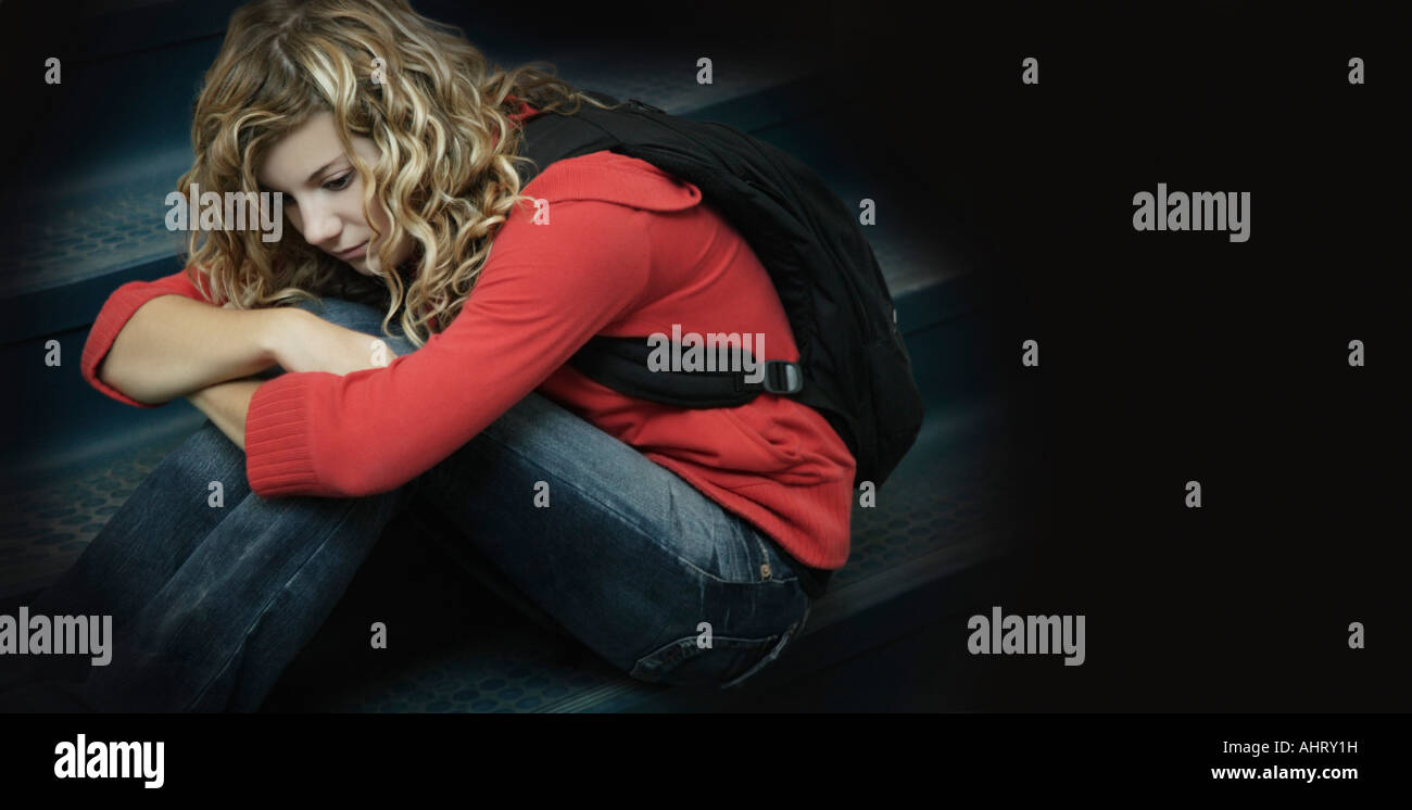 Sad girl sitting alone Stock Photo - Alamy