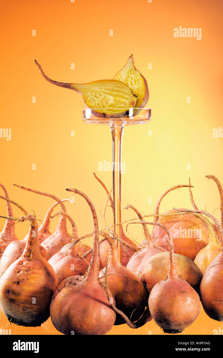 Whole golden beets on a yellow orange background. One beet sliced in ...
