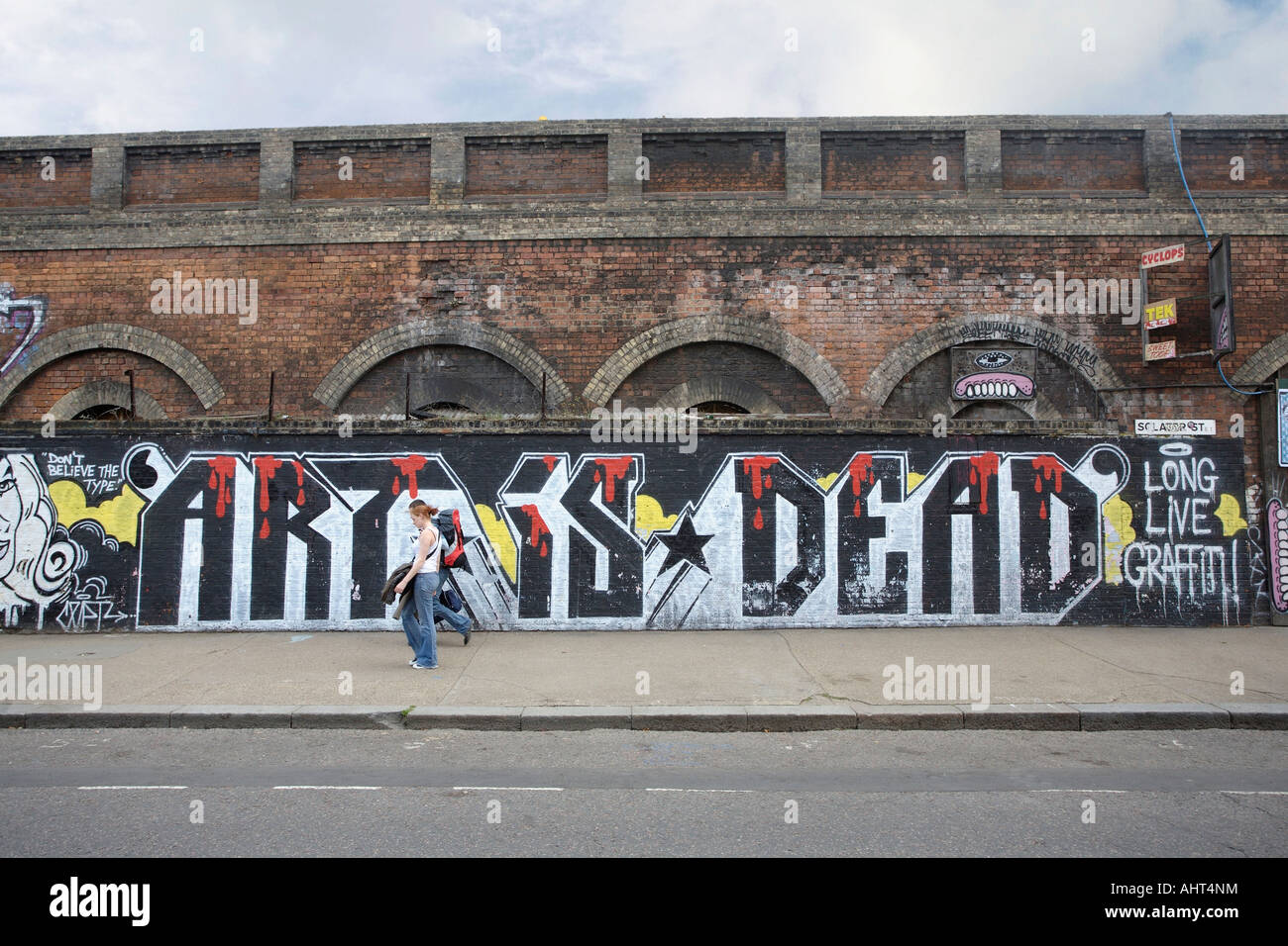 Couple walking past graffiti. Sclater Street, Shoreditch, Hackney ...