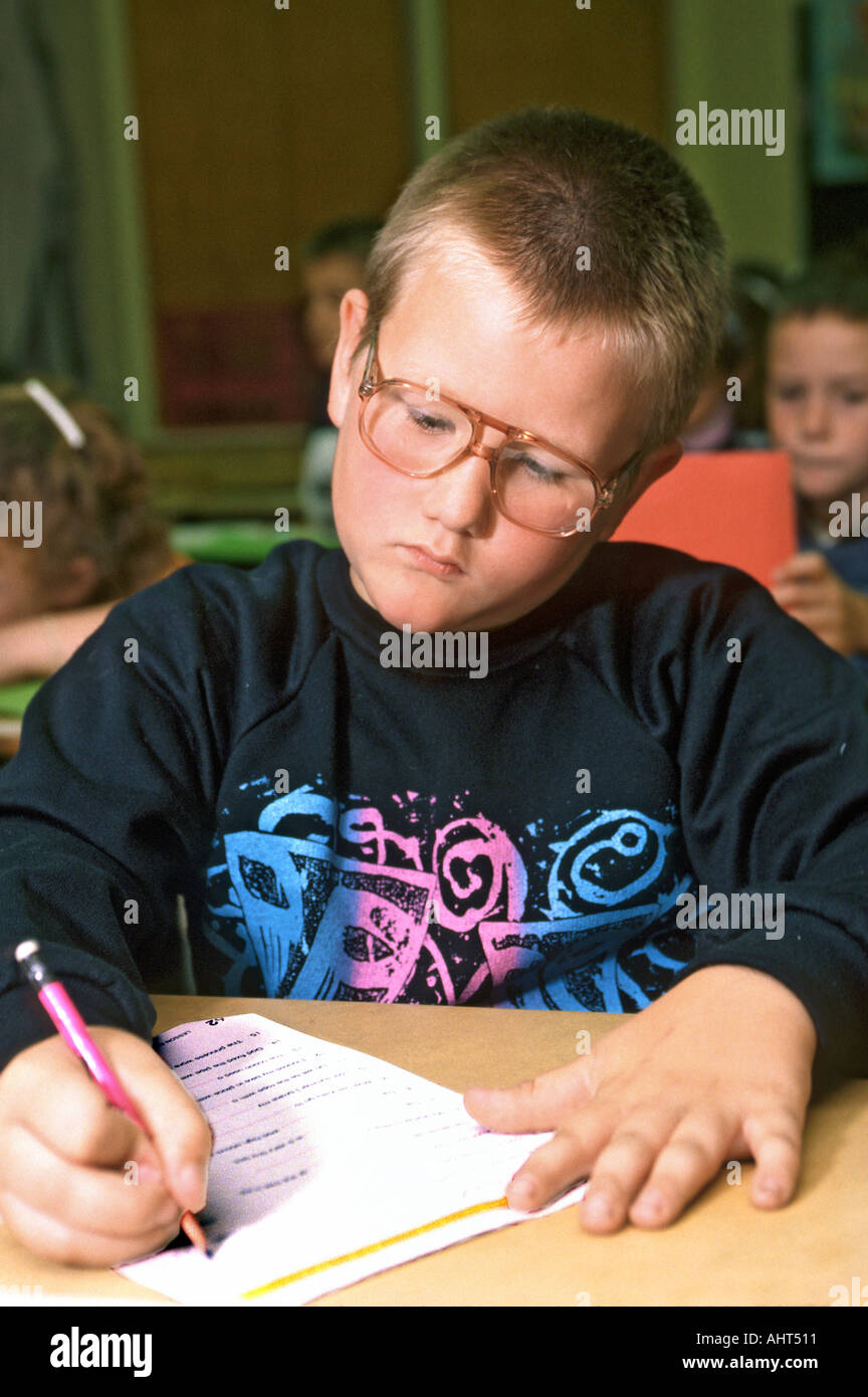3rd grade male wearing glasses working on school paper Stock Photo - Alamy