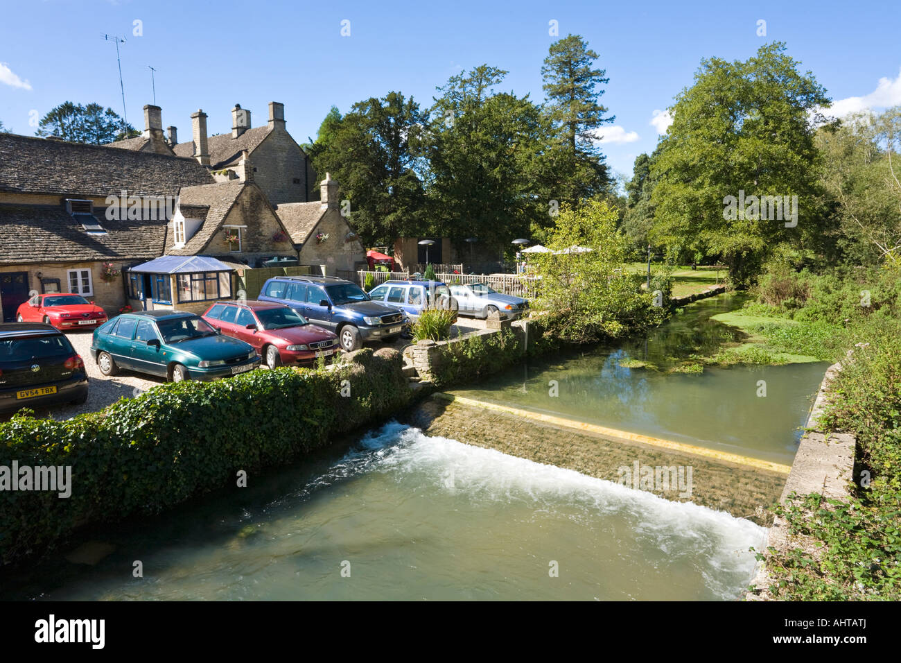 The River Coln flowing over a weir beside The Inn at Fossebridge in the ...