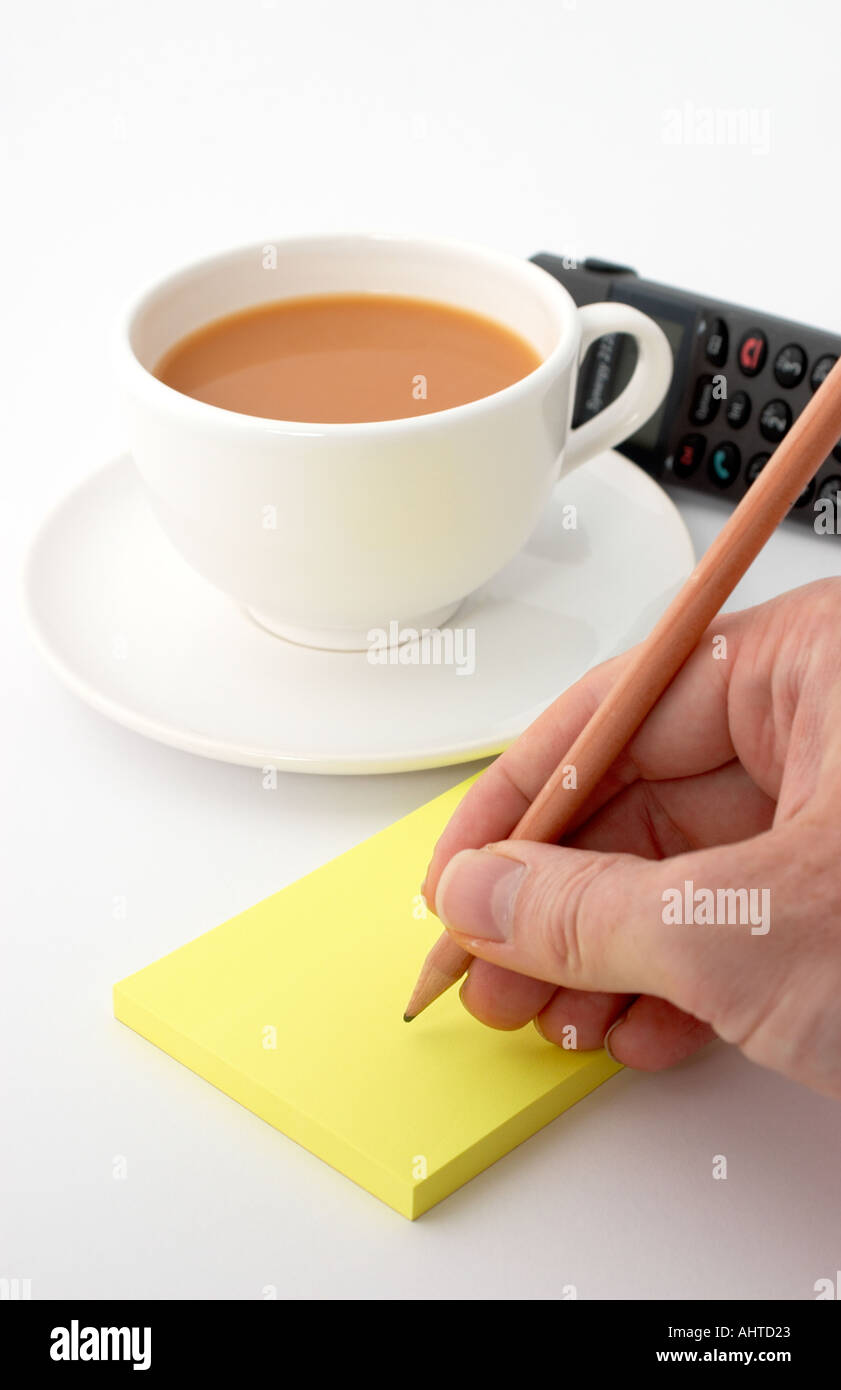 writing a reminder on a post it note Stock Photo - Alamy