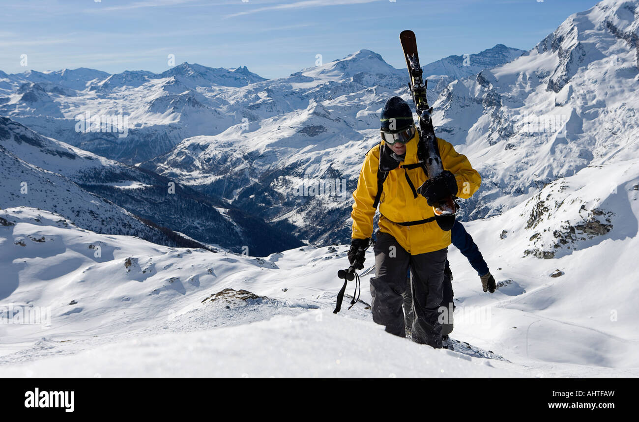 Two male skiers walking up mountain ridge carrying skis Stock Photo - Alamy