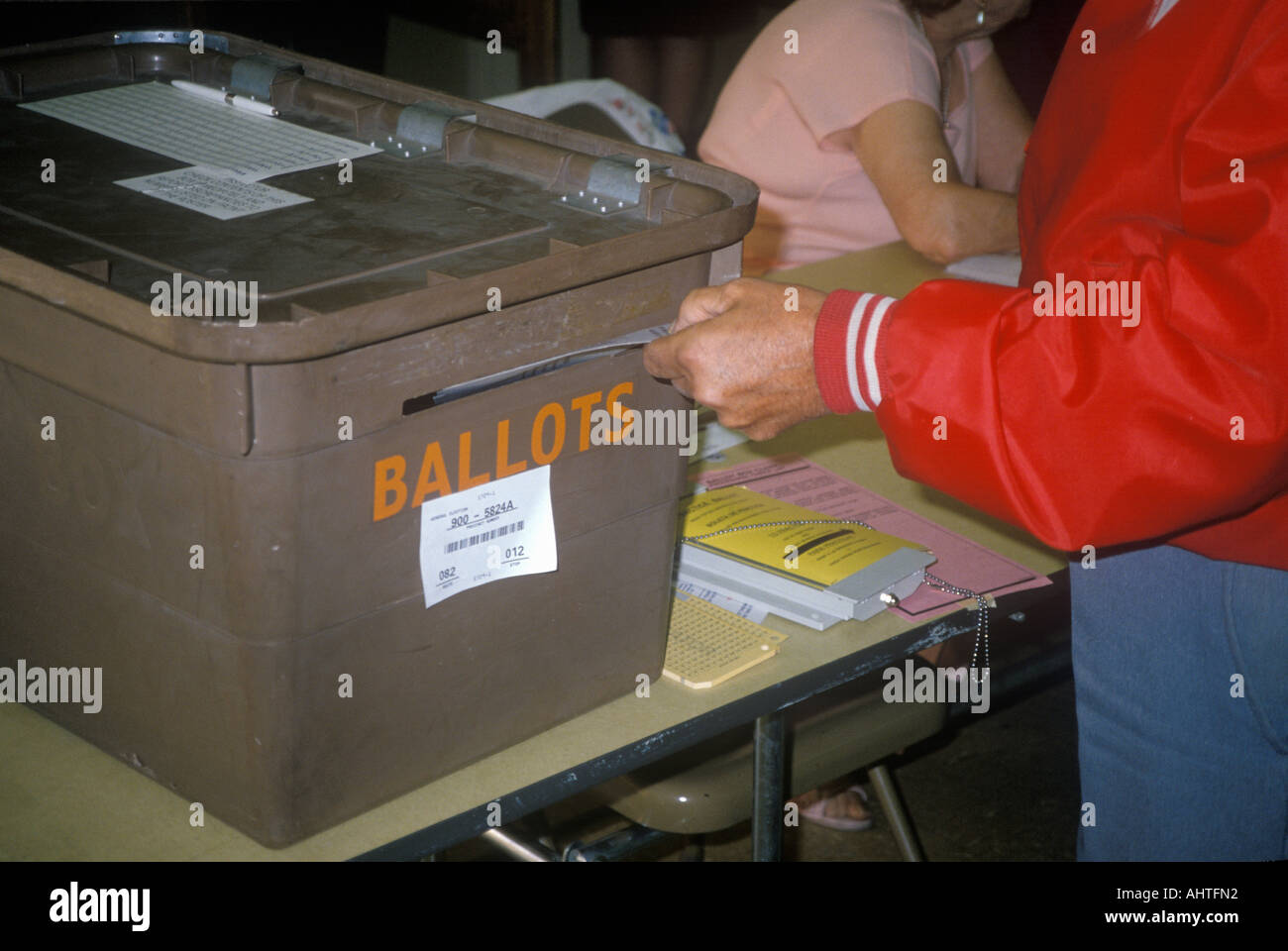 Election volunteer depositing ballots in a ballot box in a polling ...