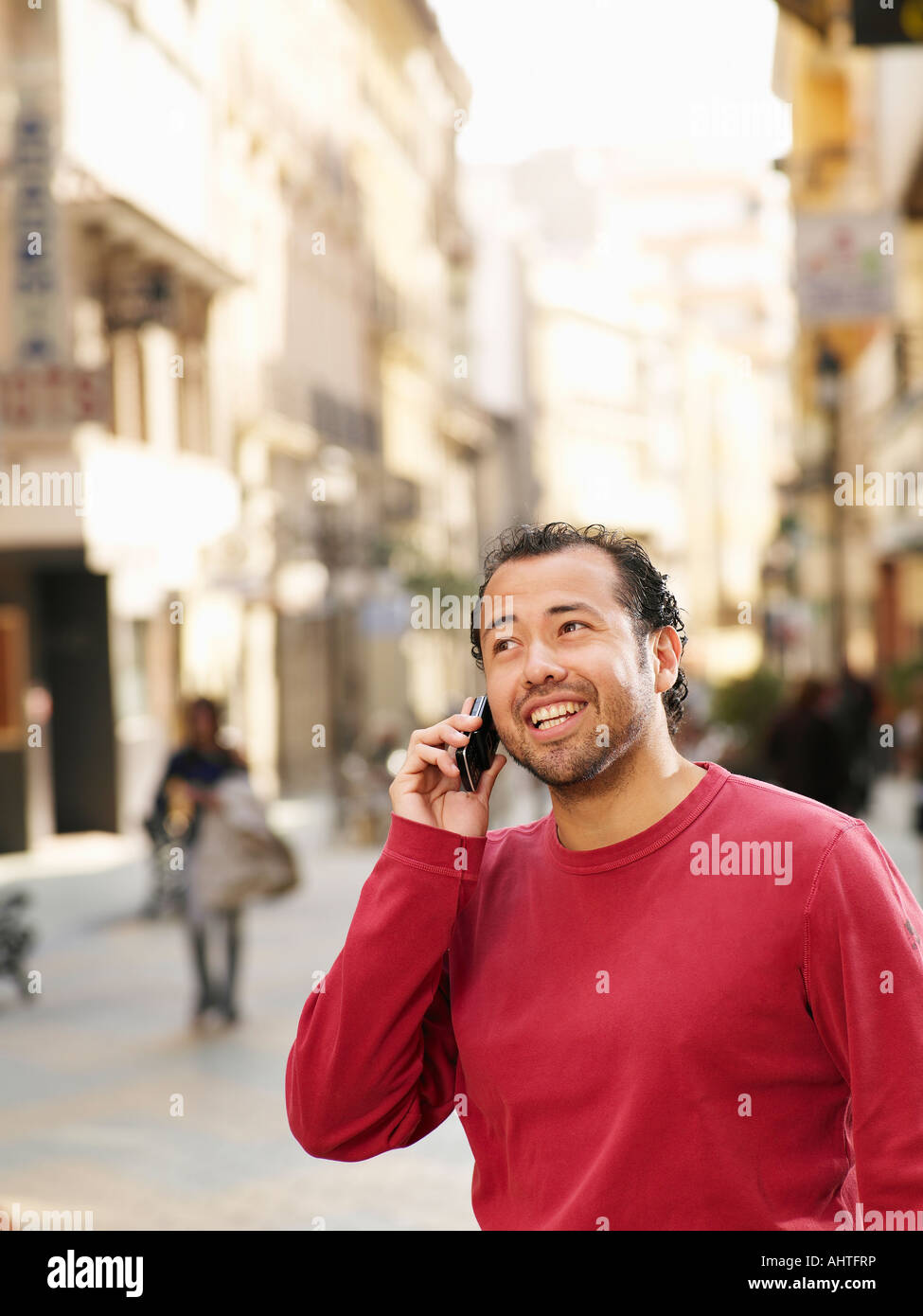 Man standing in street using mobile phone, smiling Stock Photo - Alamy