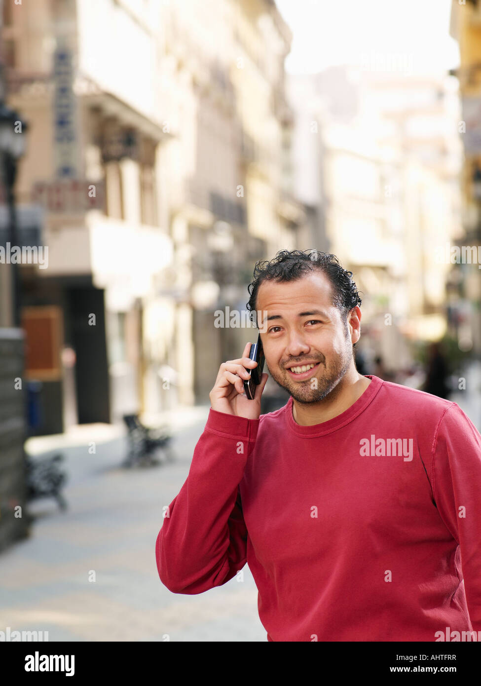 Man standing in street using mobile phone, smiling, portrait Stock ...