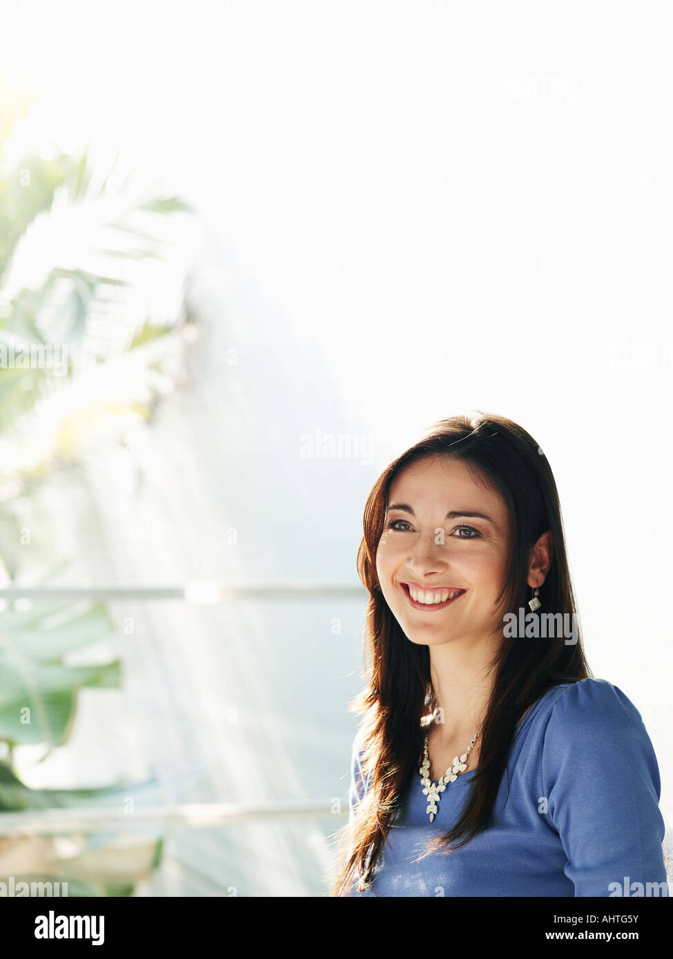 Woman standing by window, smiling Stock Photo - Alamy