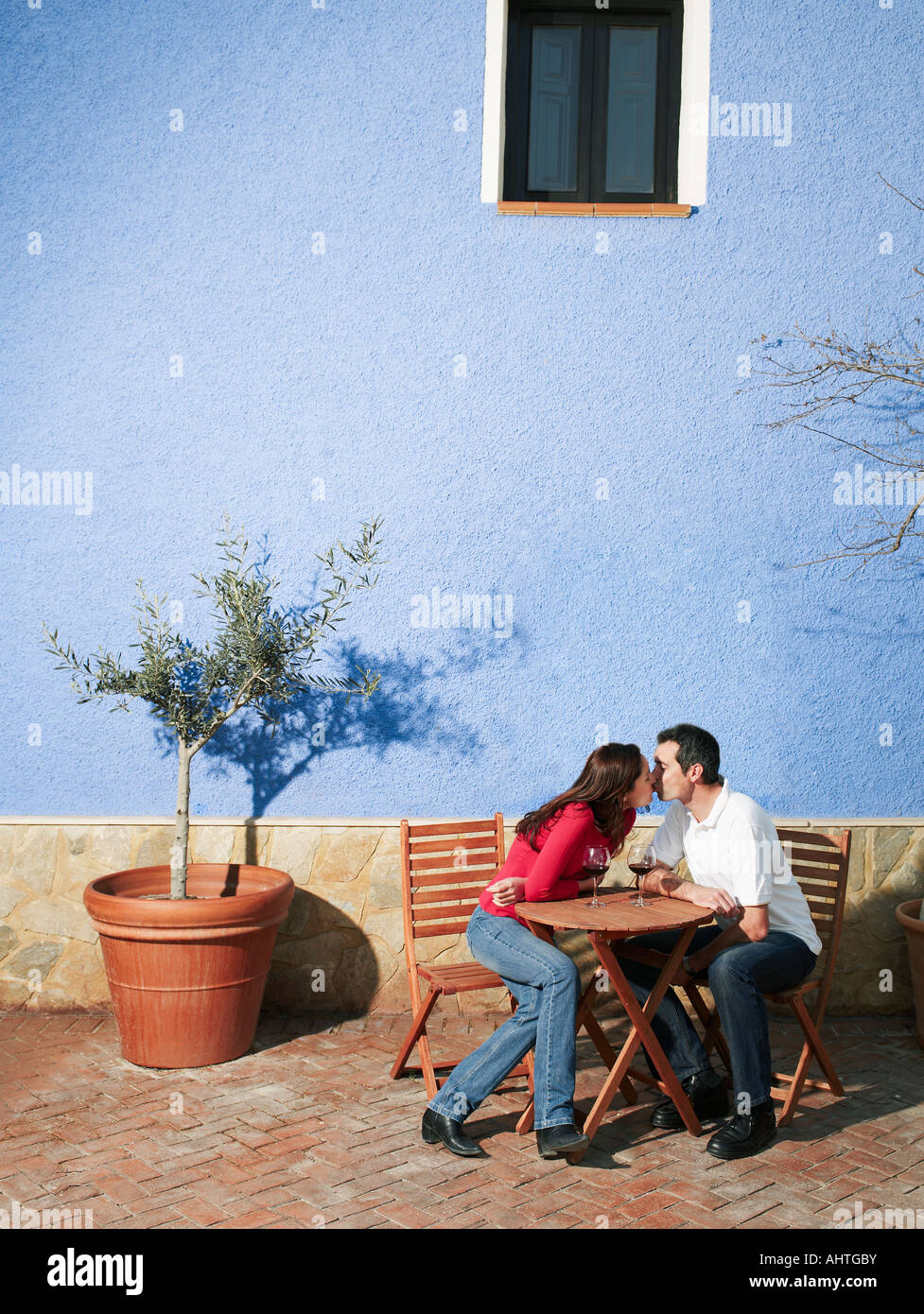 Couple sitting on garden terrace, kissing Stock Photo - Alamy