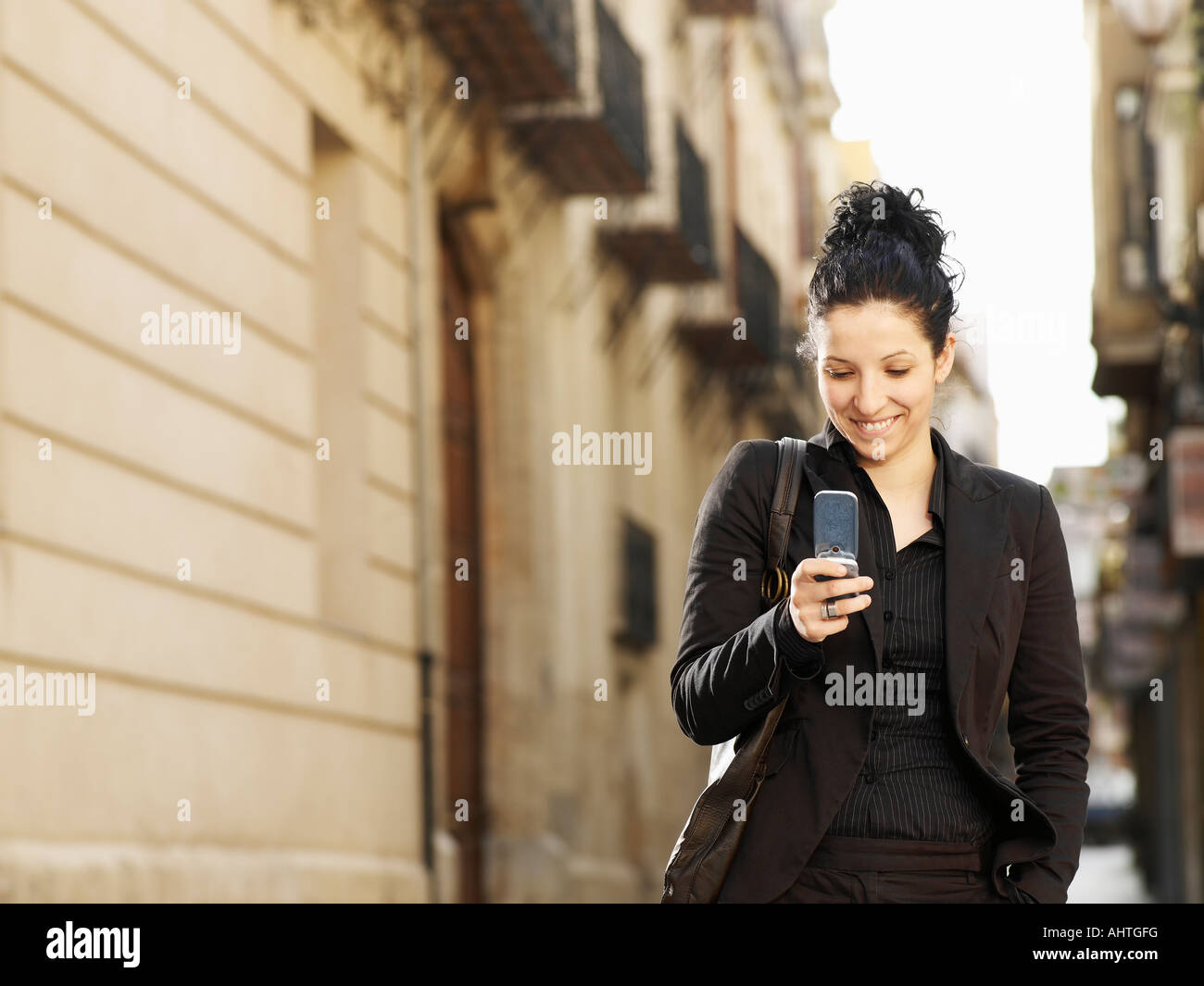 Young woman walking in street using mobile phone, smiling Stock Photo ...
