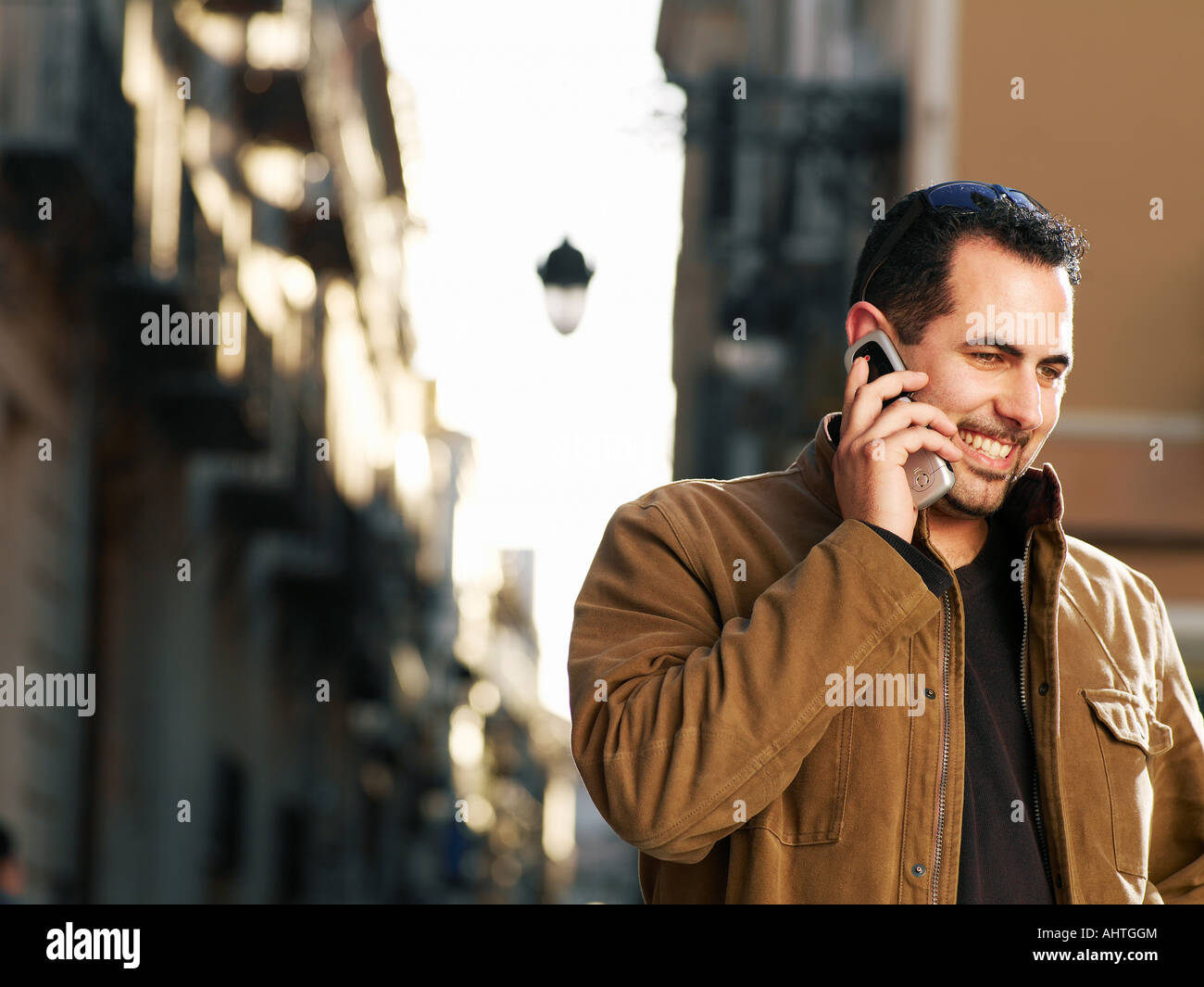 Young man using mobile phone in street, smiling Stock Photo - Alamy