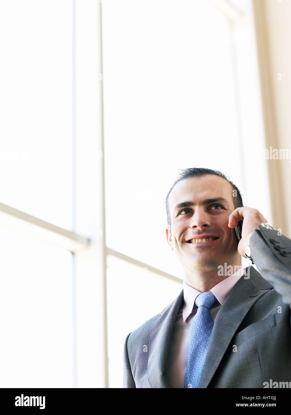 Businessman using mobile phone, smiling, low angle view Stock Photo - Alamy