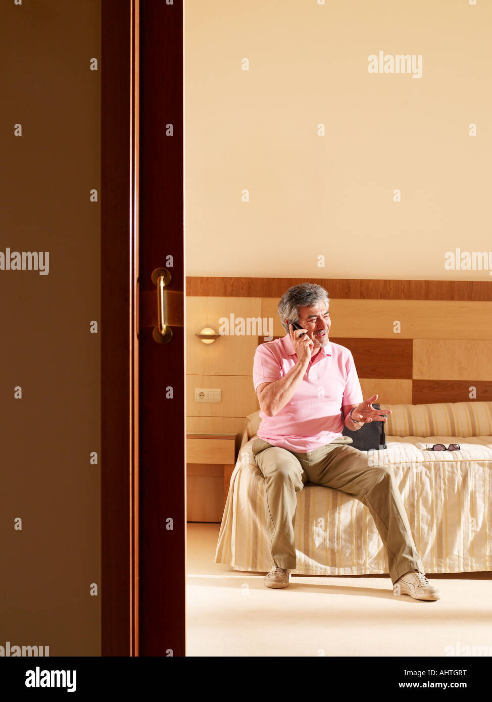 Senior man sitting in hotel room using cell phone Stock Photo - Alamy