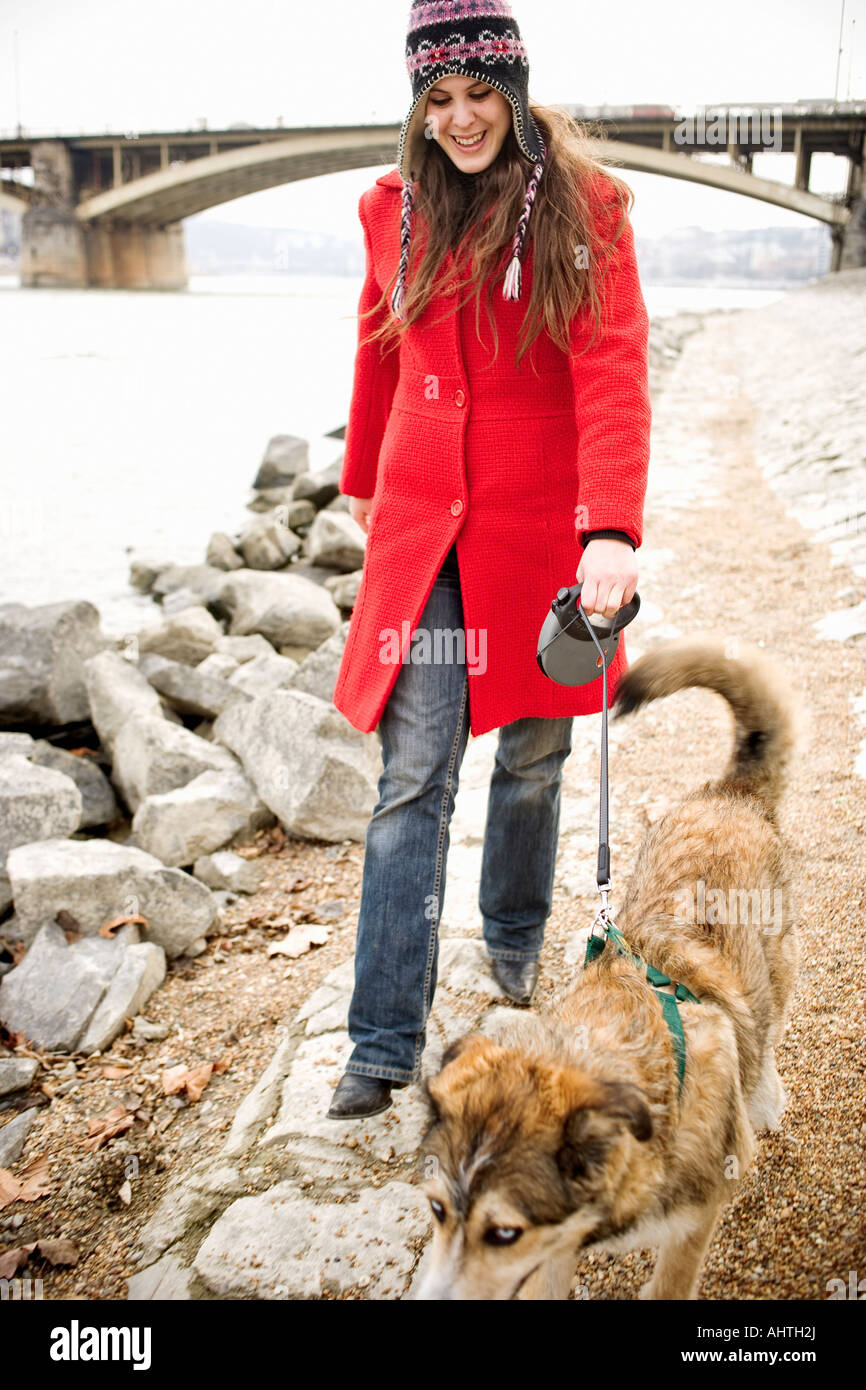 Young woman walking dog on lead by river, smiling Stock Photo - Alamy