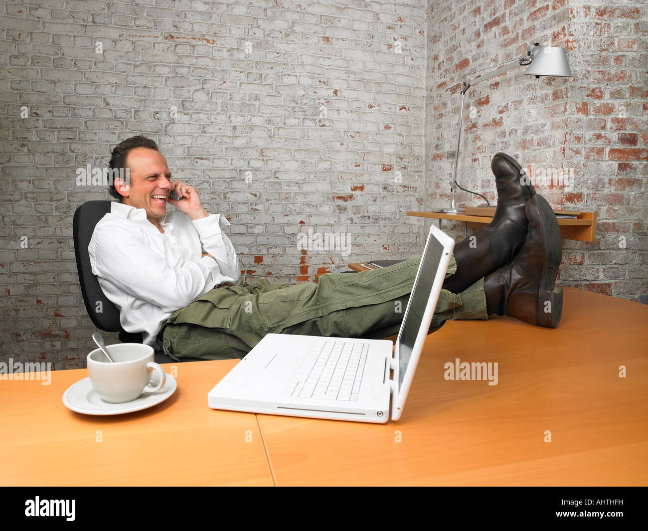 Businessman laughing on the phone, feet on desk. ,Brussels, Belgium ...