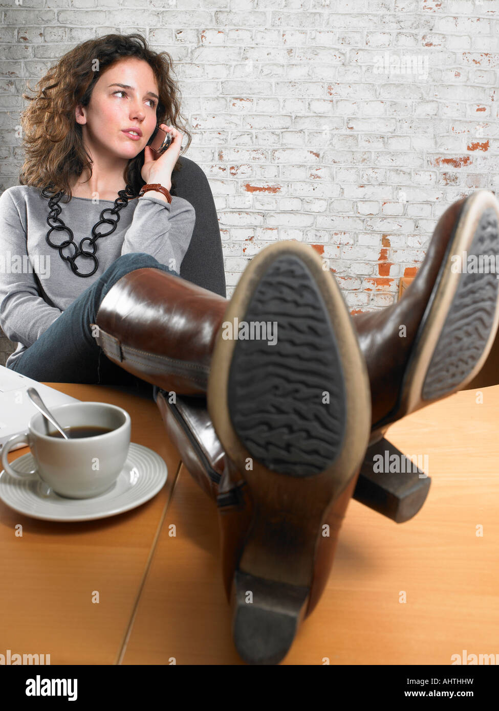 Businesswoman talking on the phone, feet up on desk. ,Brussels, Belgium ...