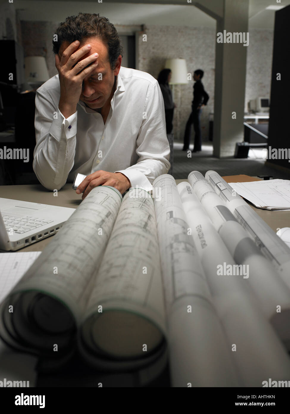 Stressed architect at desk, two females in background. Brussels ...