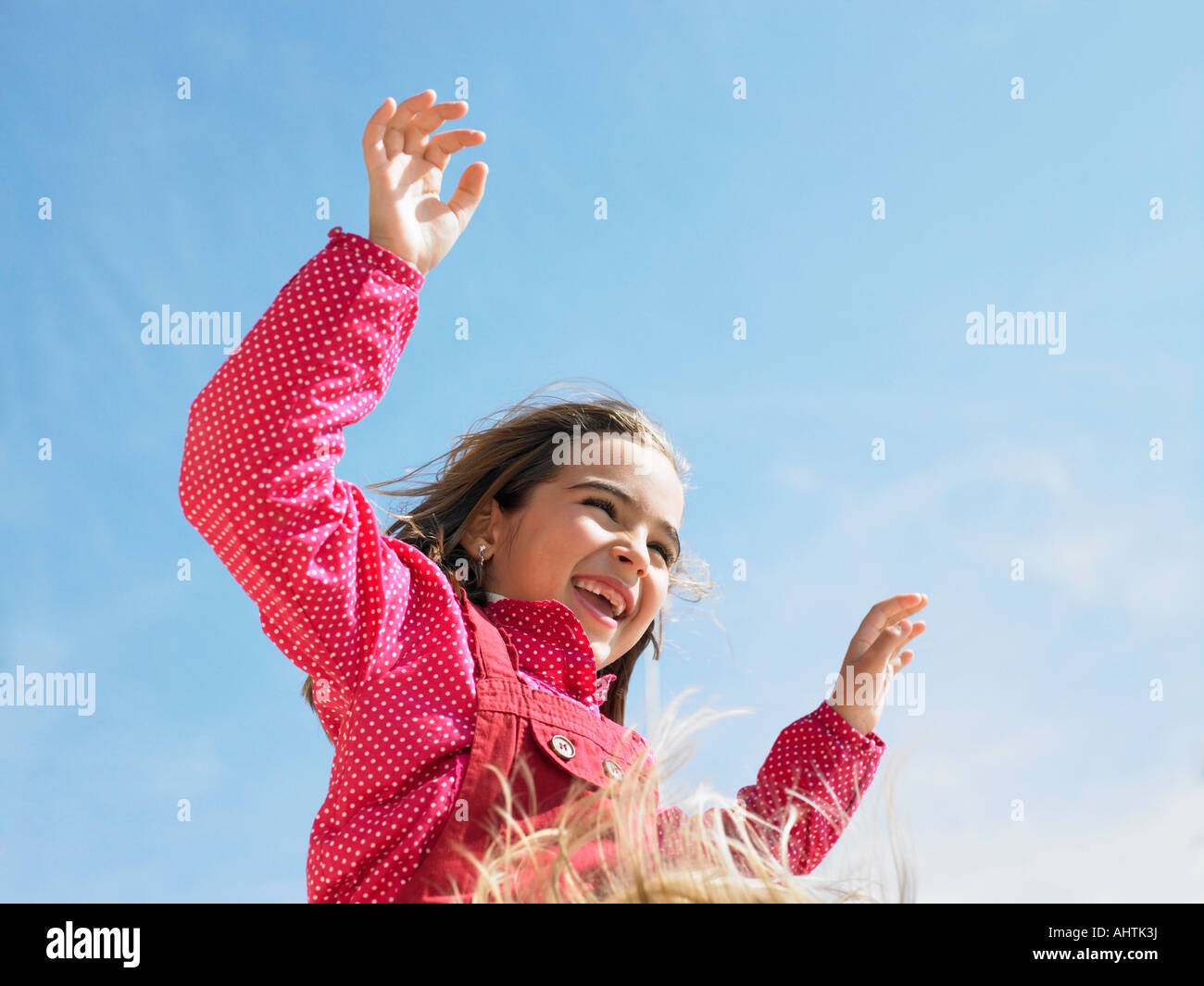 Low angle view of young girl (5-7) with arms raised on shoulders Stock ...