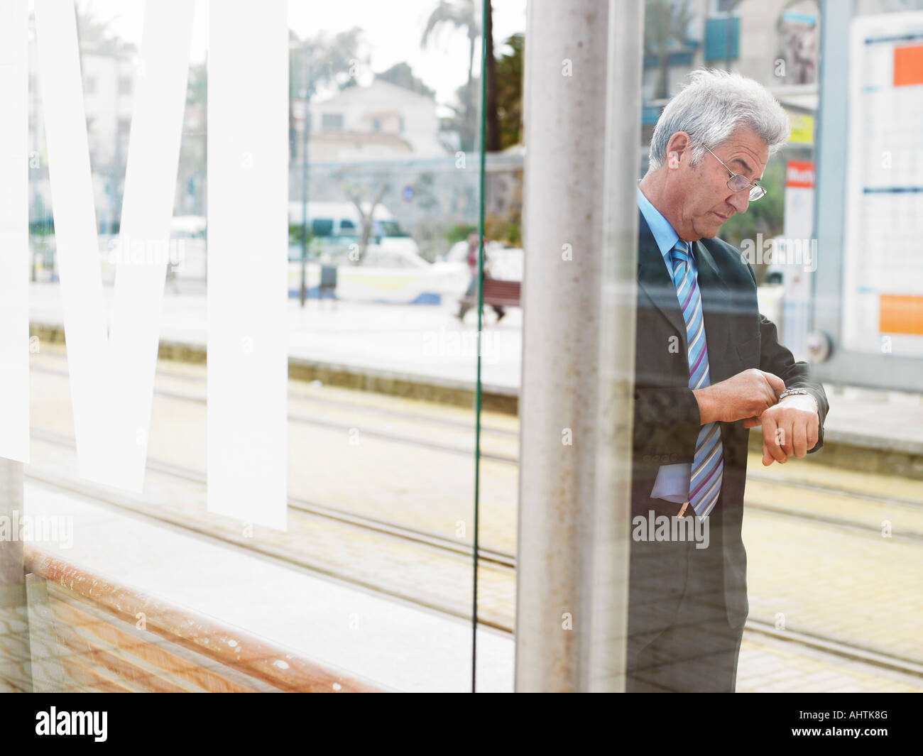 Senior businessman checking watch waiting by tramway Stock Photo - Alamy