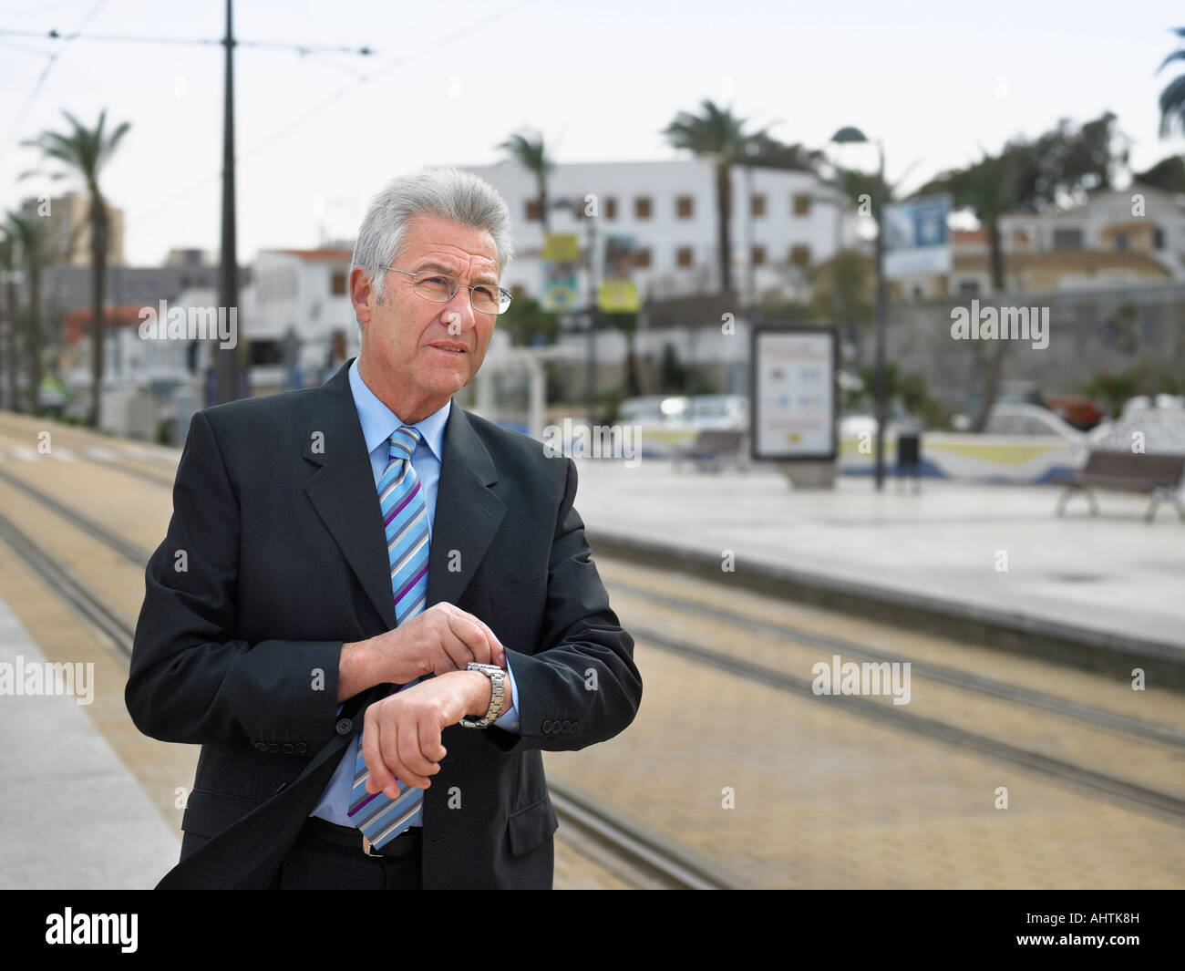 Senior businessman checking watch waiting by tramway Stock Photo - Alamy