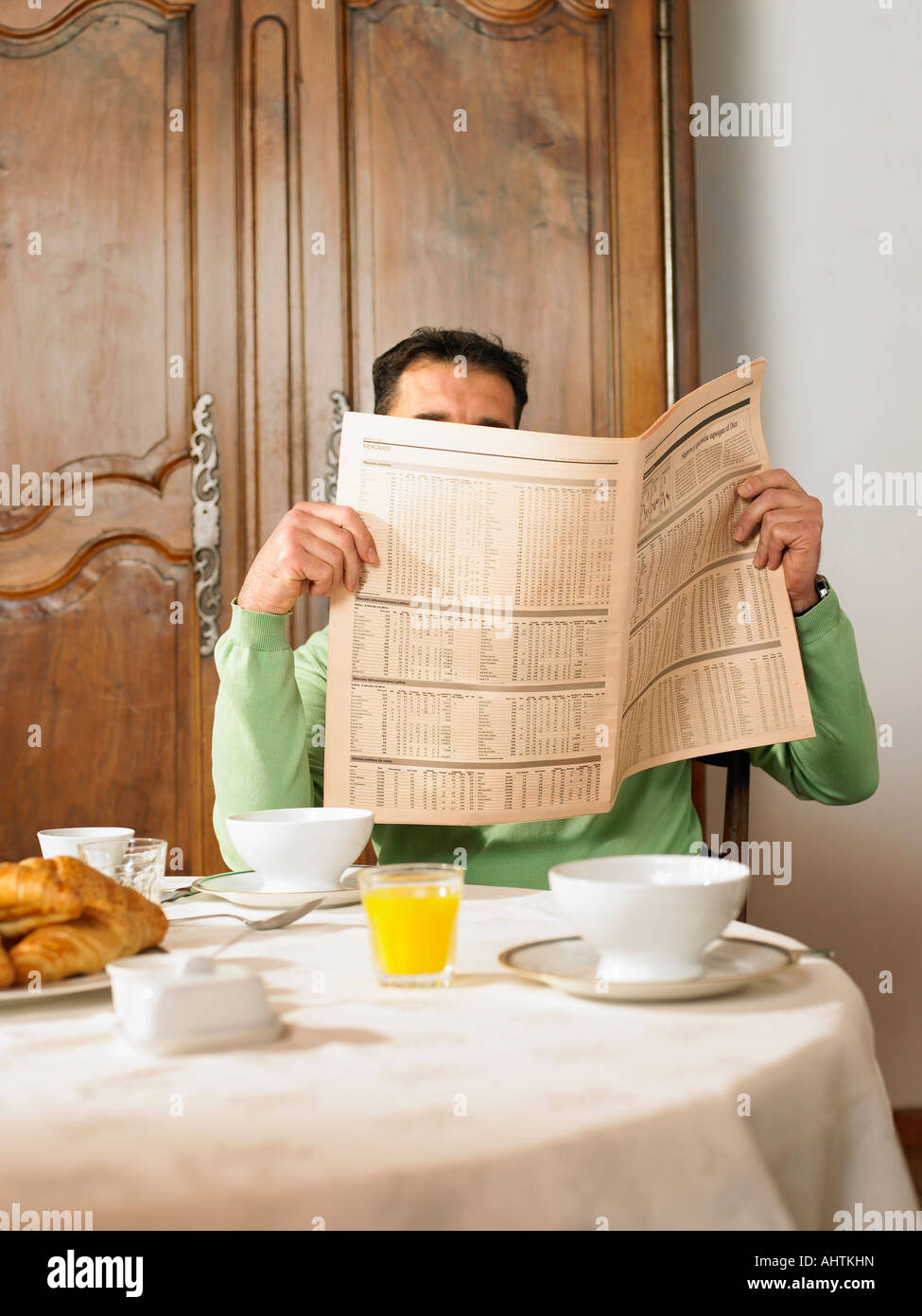 Man sitting at breakfast table reading newspaper Stock Photo - Alamy