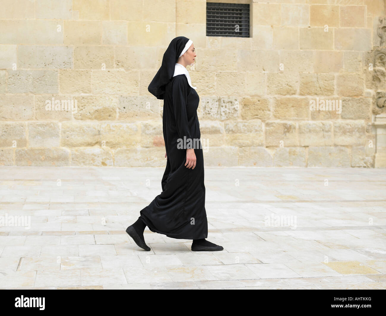 Nun walking in front of stone wall, Alicante, Spain Stock Photo - Alamy