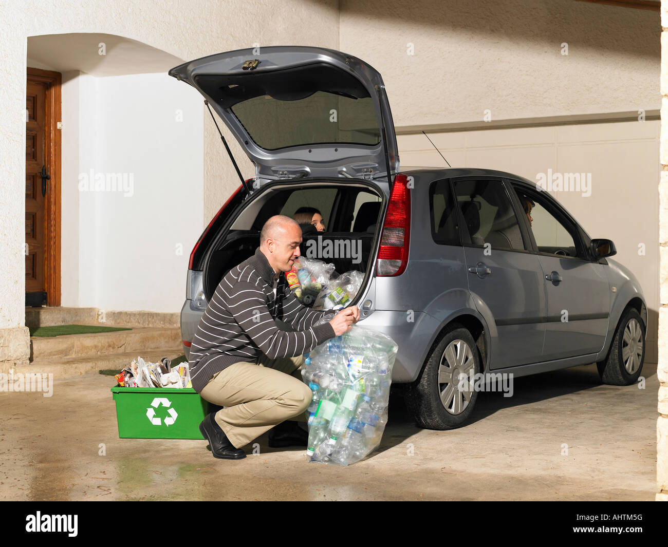 Man loading recycling into car Stock Photo - Alamy