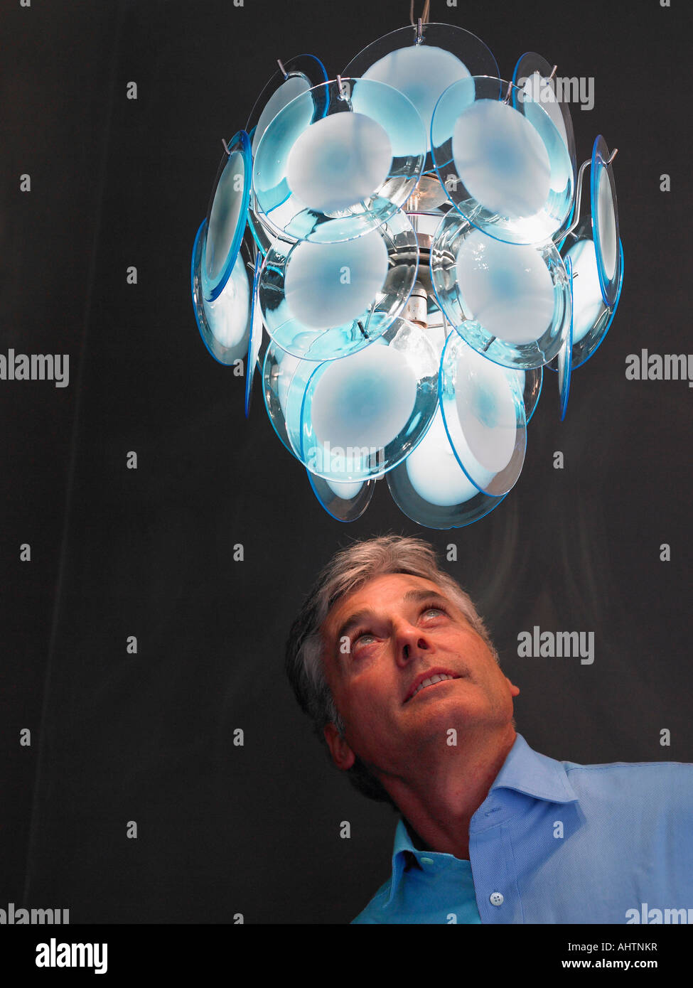 Mature man standing under illuminated chandelier Stock Photo - Alamy