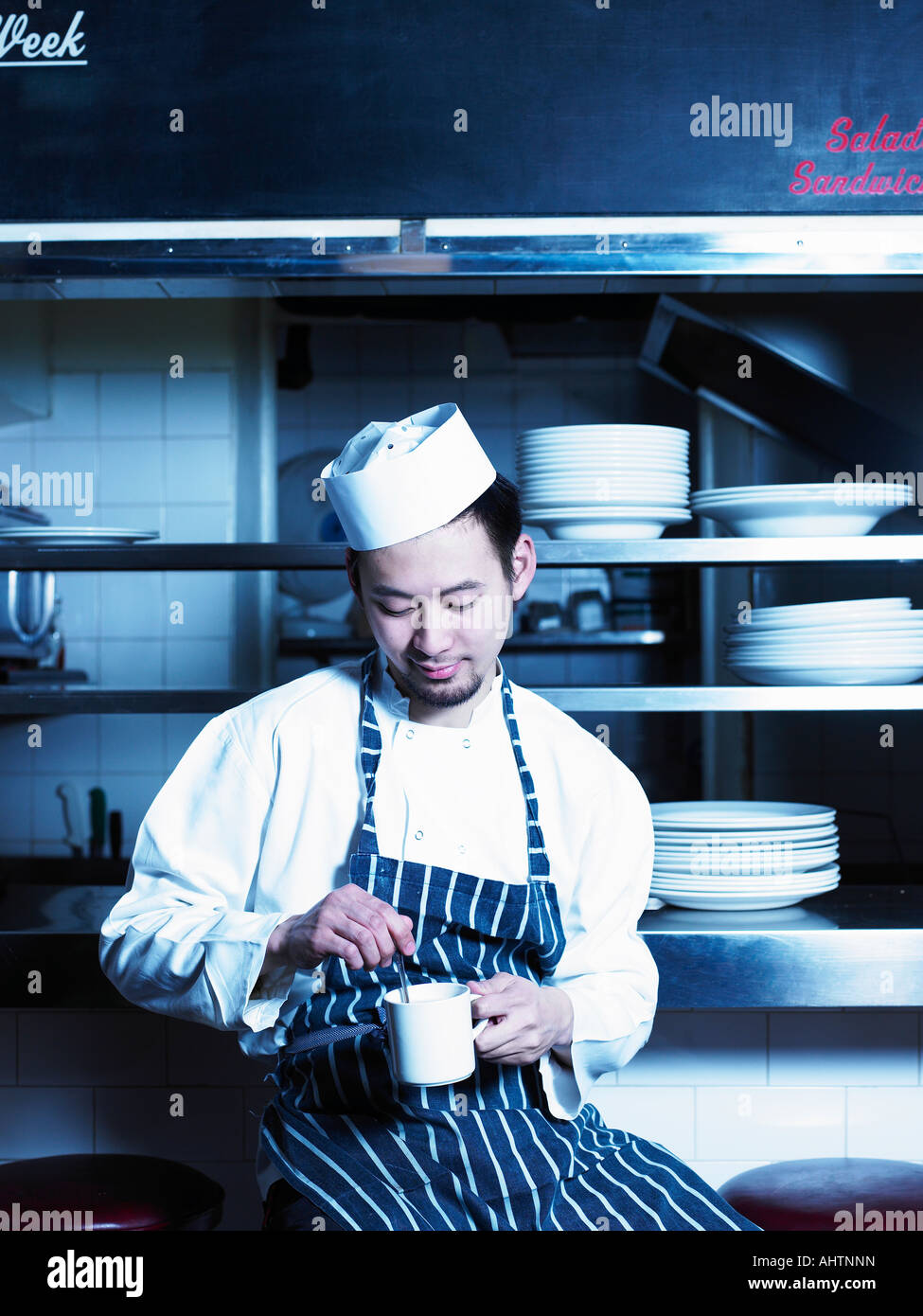 Young chef taking break in kitchen holding cup, smiling Stock Photo - Alamy