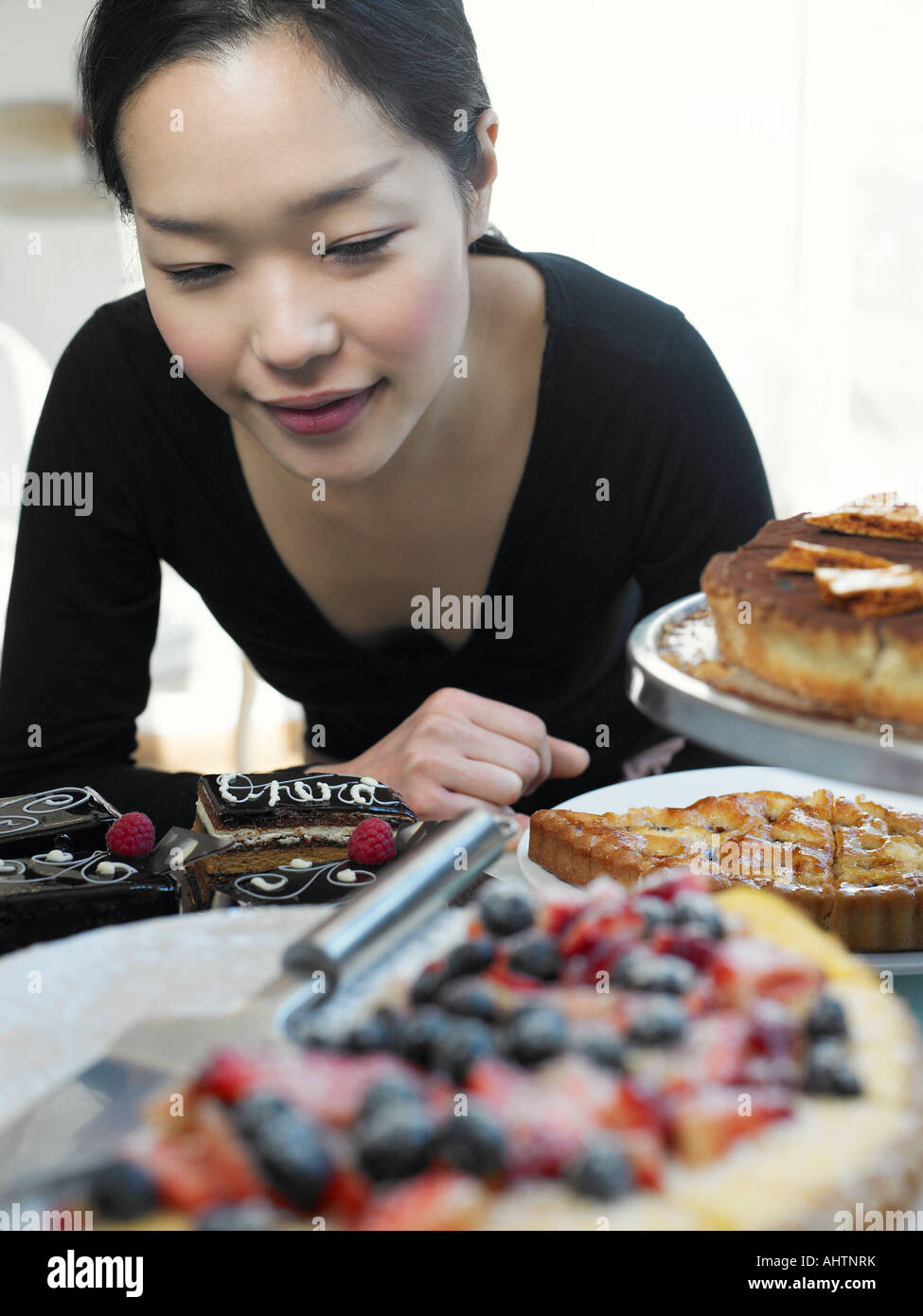 Young woman looking at cake display, smiling Stock Photo - Alamy