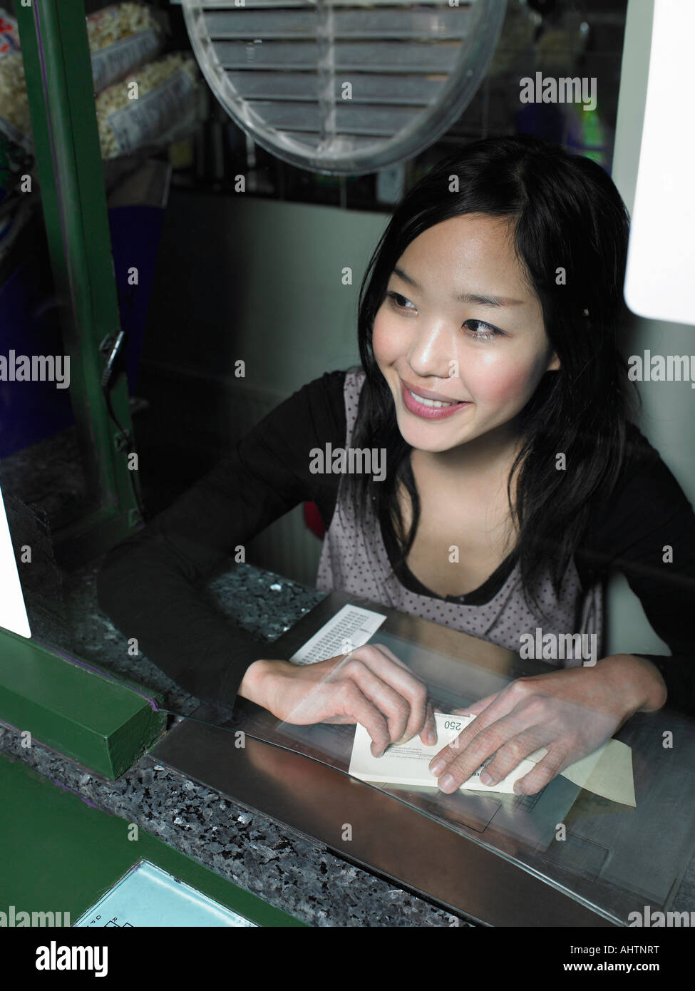 Young female cashier selling tickets at cinema kiosk, smiling Stock Photo - Alamy