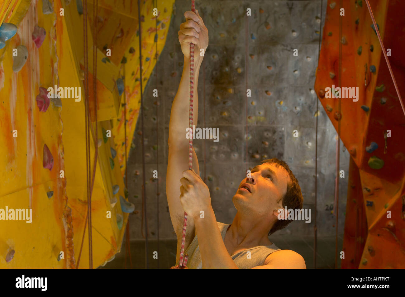 Man climbing up rope at indoor climbing centre Stock Photo - Alamy