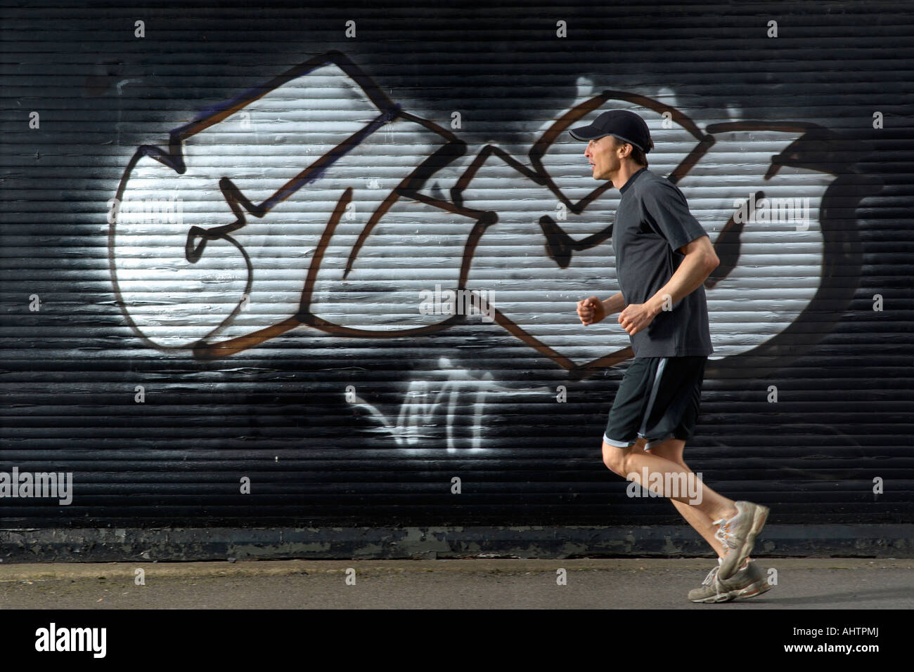 Male runner passing graffiti in street, side view Stock Photo - Alamy