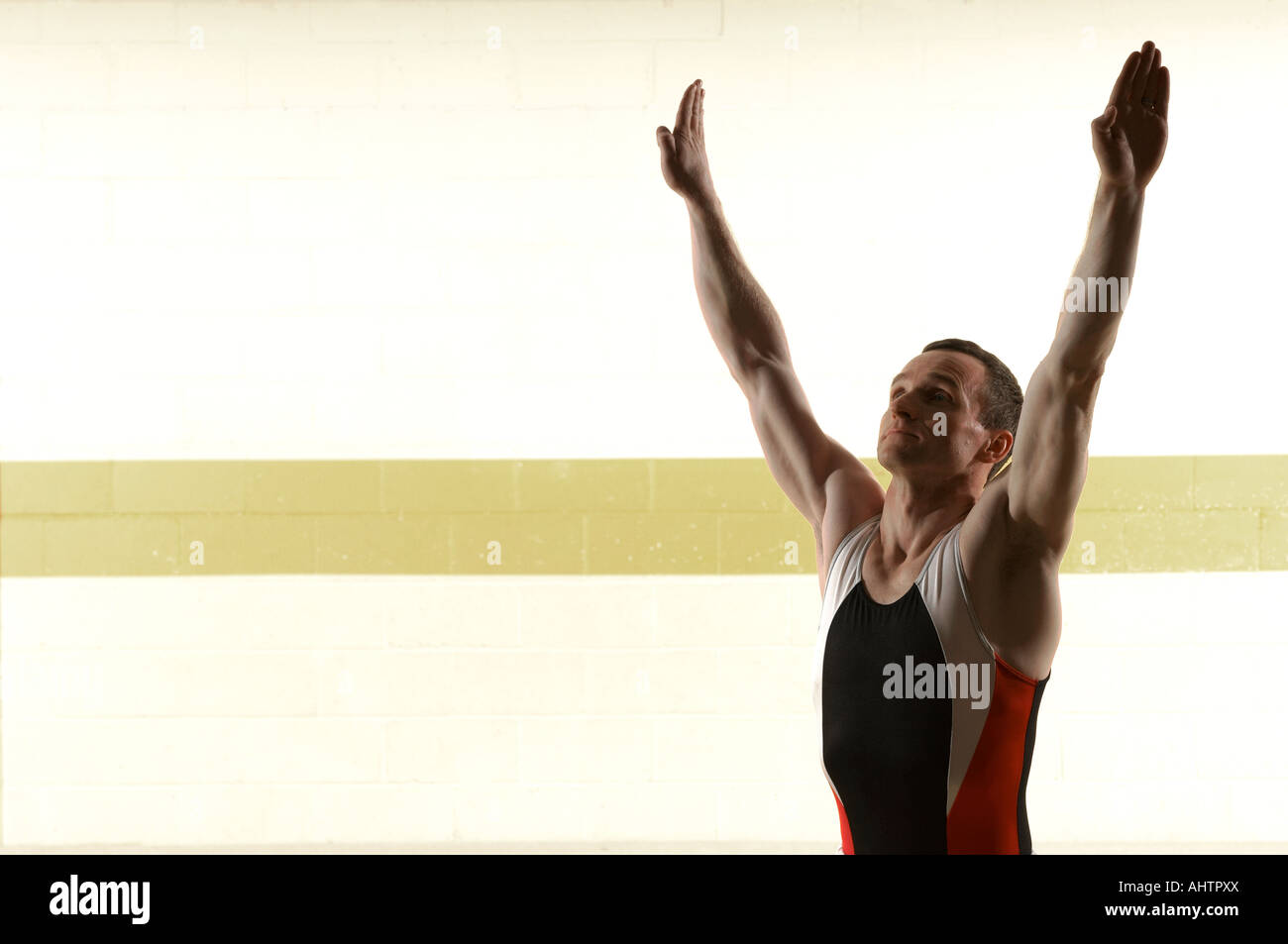 Male gymnast standing with arms raised above head Stock Photo - Alamy