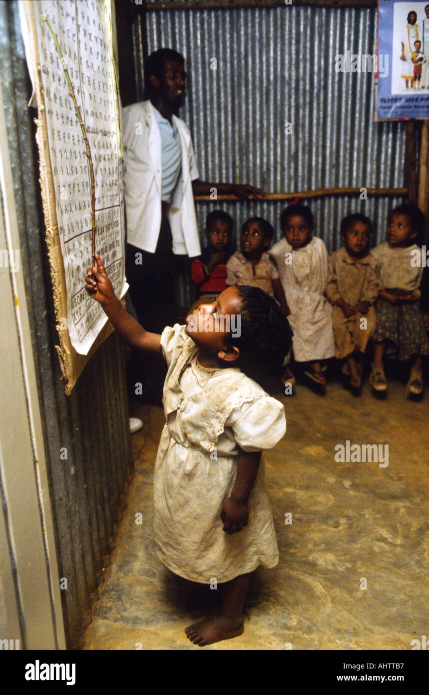 Young children and teacher in a makeshift classroom in a slum area ...