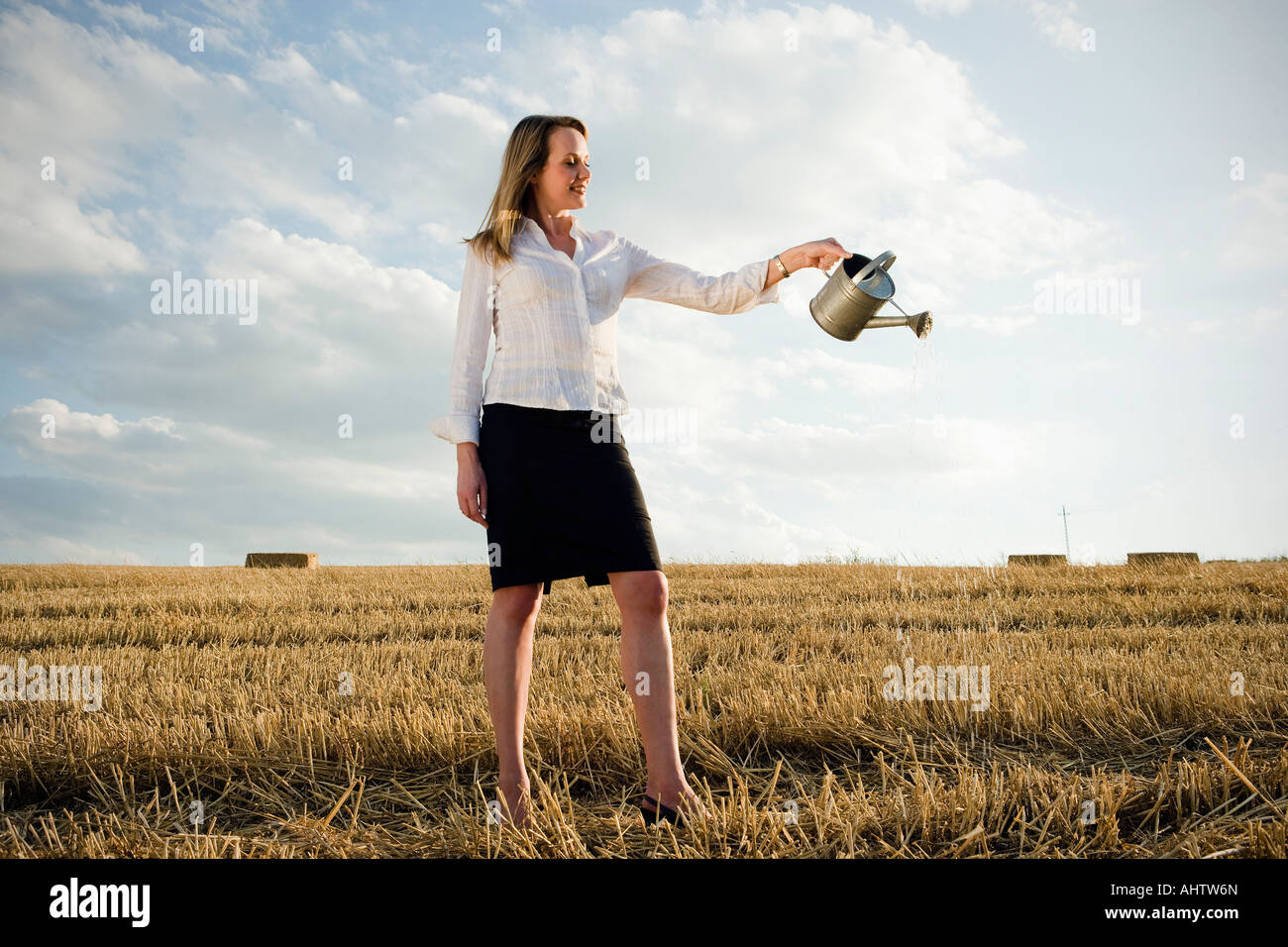 Woman pouring water on wheat field Stock Photo - Alamy