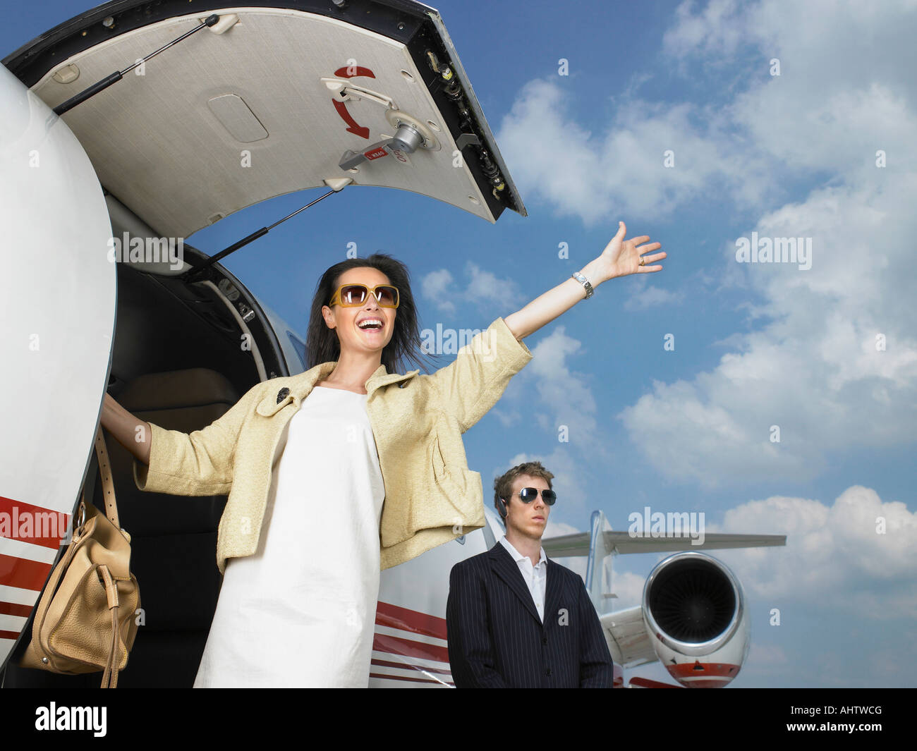 Smiling woman exiting private jet with bodyguard Stock Photo - Alamy