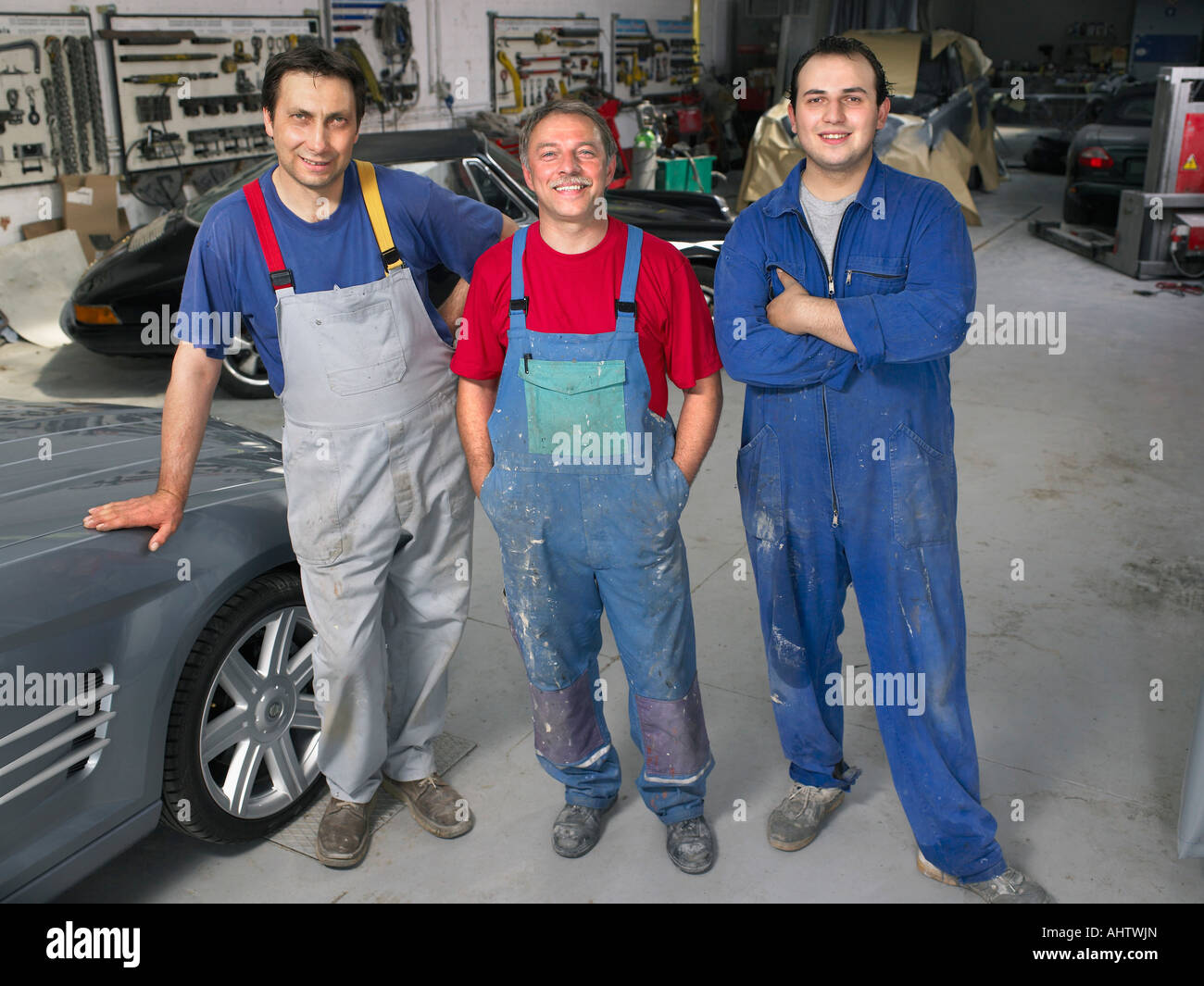 Three workers in a garage Stock Photo - Alamy