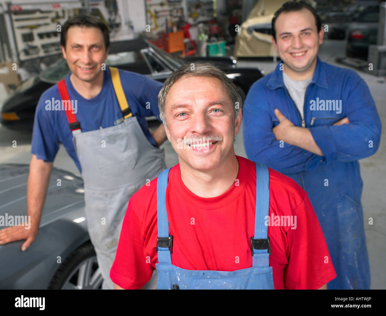 Three workers in a garage portrait Stock Photo - Alamy