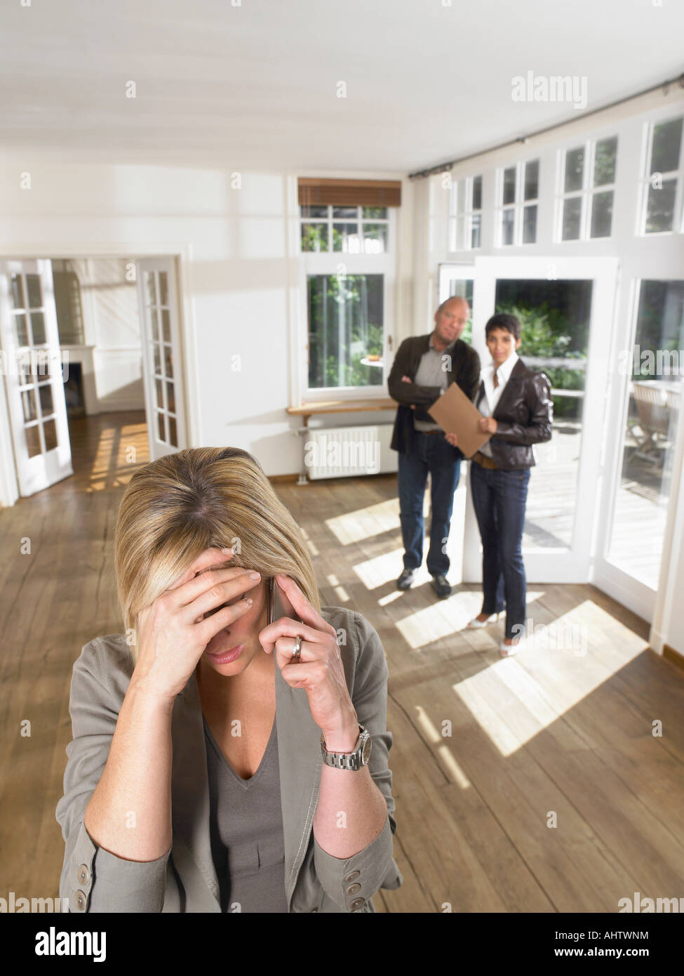 Frustrated real estate agent on phone with clients behind Stock Photo ...