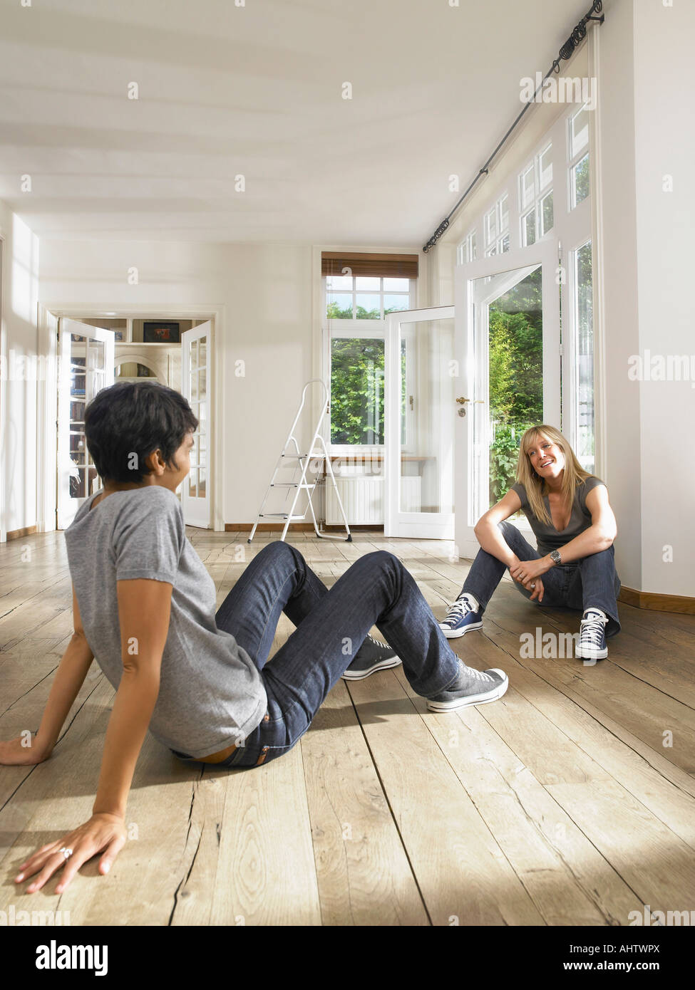 Two friends seated on floor of empty house Stock Photo - Alamy