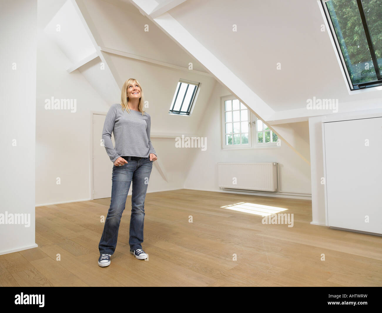 Woman standing and looking up inside empty white loft Stock Photo - Alamy