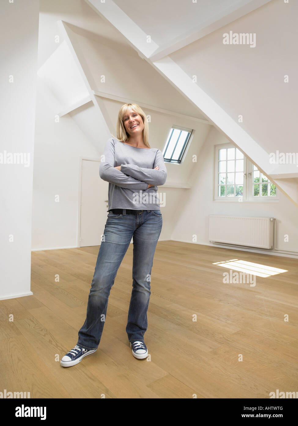 Woman standing with arms crossed in an empty loft Stock Photo - Alamy