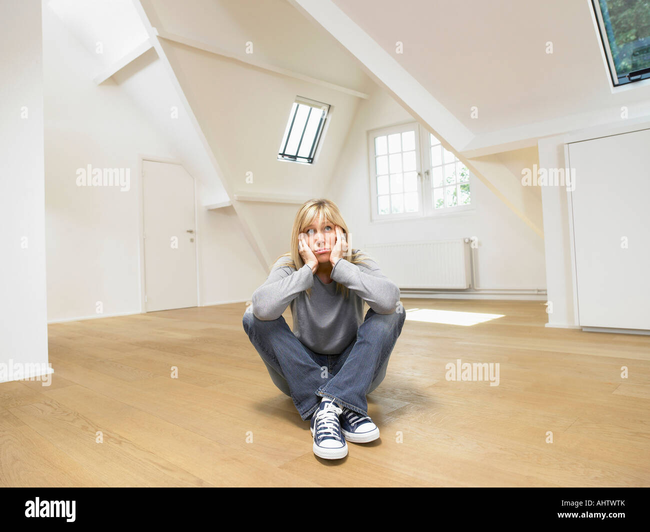 Sad-looking woman on floor in empty loft Stock Photo - Alamy