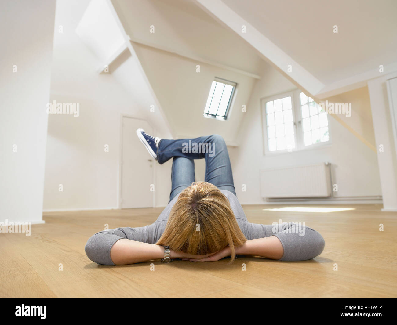 Woman resting on her back on the wooden floor of empty white loft Stock ...