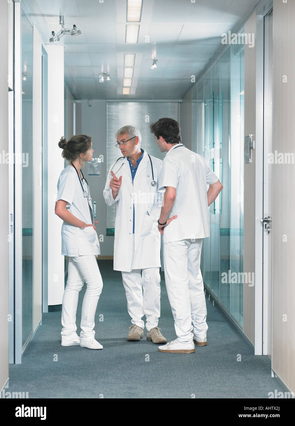 Three doctors in discussion in hospital lobby Stock Photo - Alamy