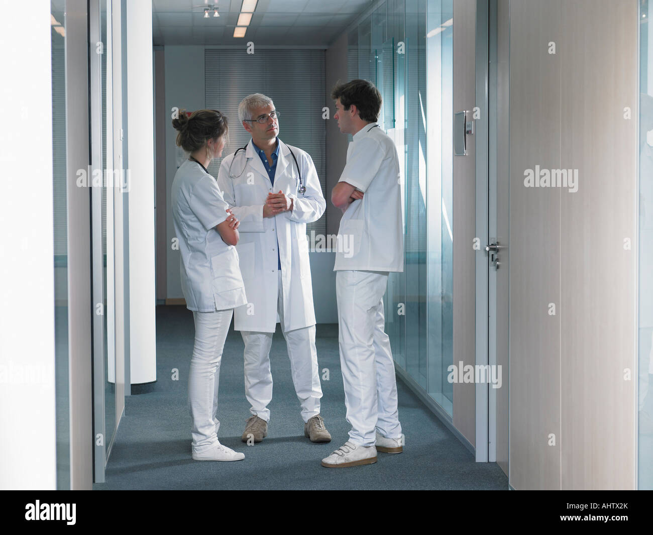 Three doctors in discussion in hospital lobby Stock Photo - Alamy