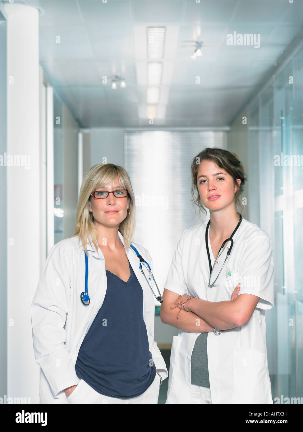 Two female doctors looking at camera in a lobby of a hospital smiling ...