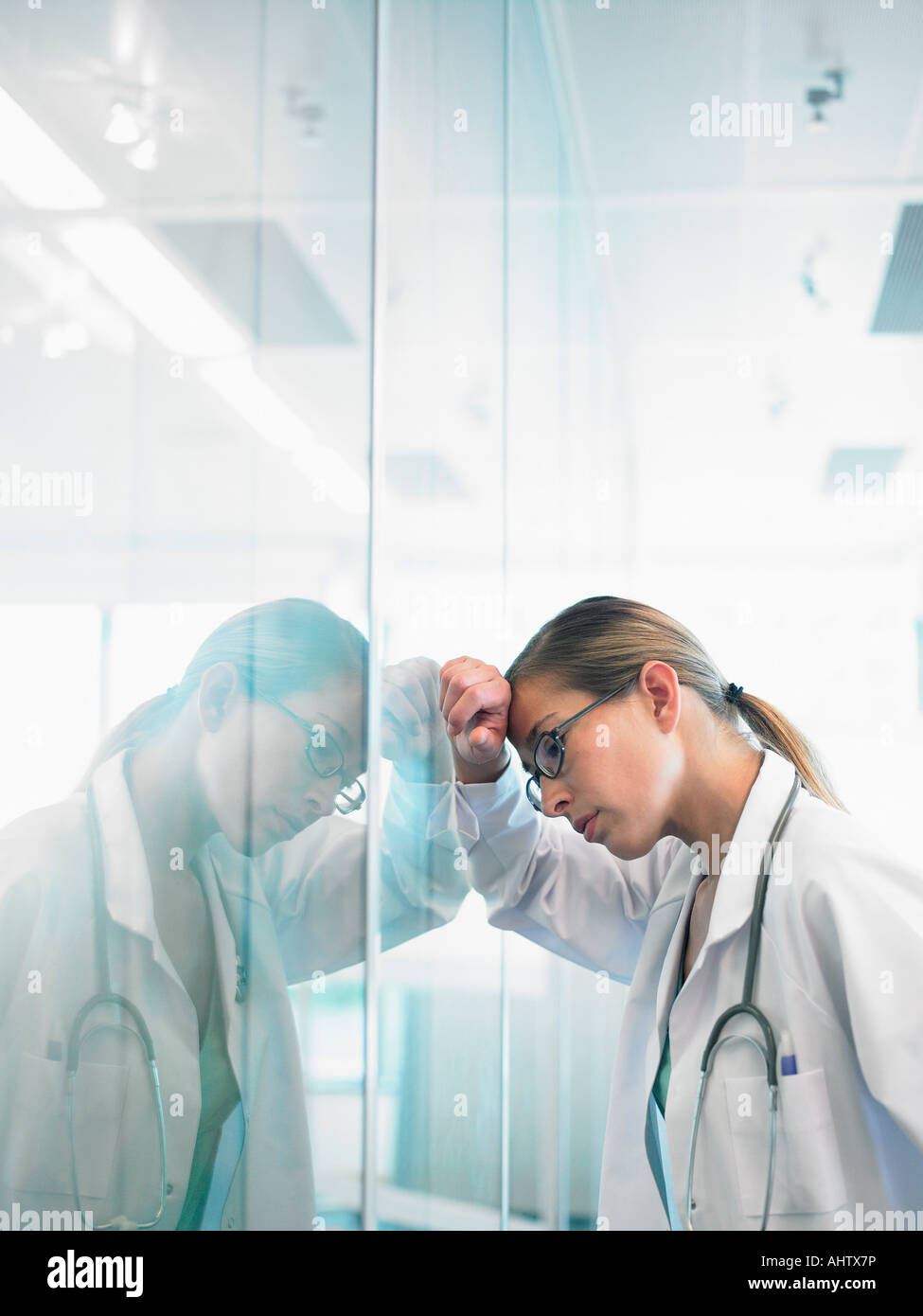 Close-up of concerned doctor leaning on glass wall in hospital lobby ...