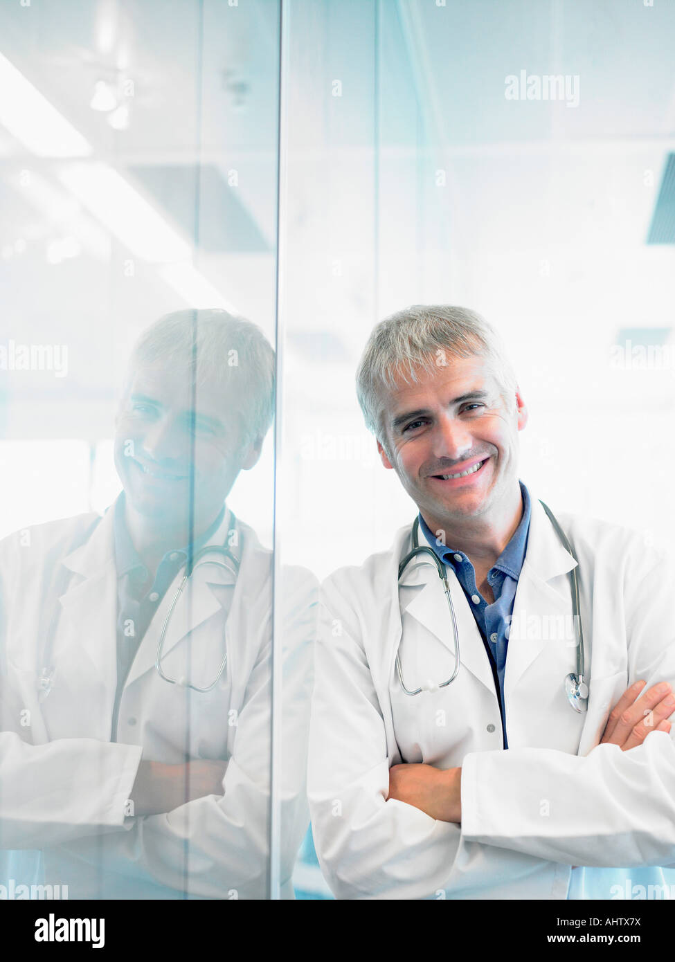 Smiling doctor leaning on wall in hospital lobby Stock Photo - Alamy